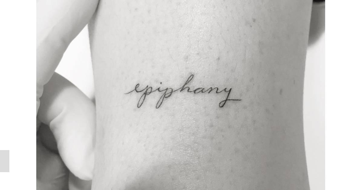 Word "epiphany" lettering tattoo located on the tricep.