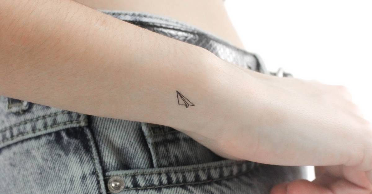 Tiny minimalistic paper plane temporary tattoo located