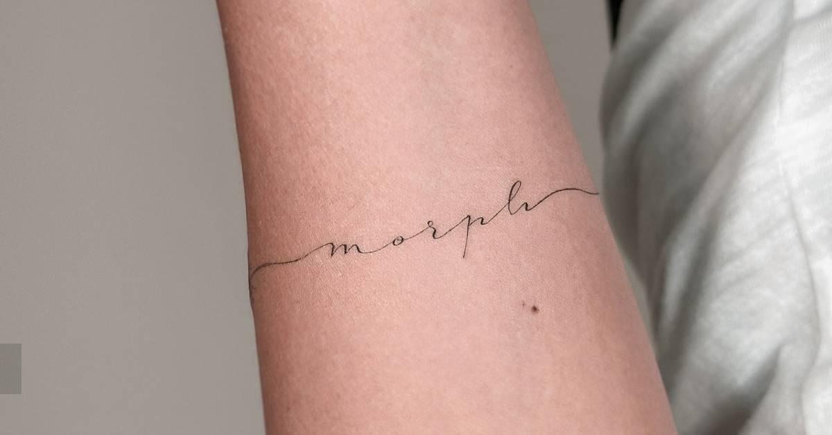 Word "morph" bracelet tattoo located on the wrist.