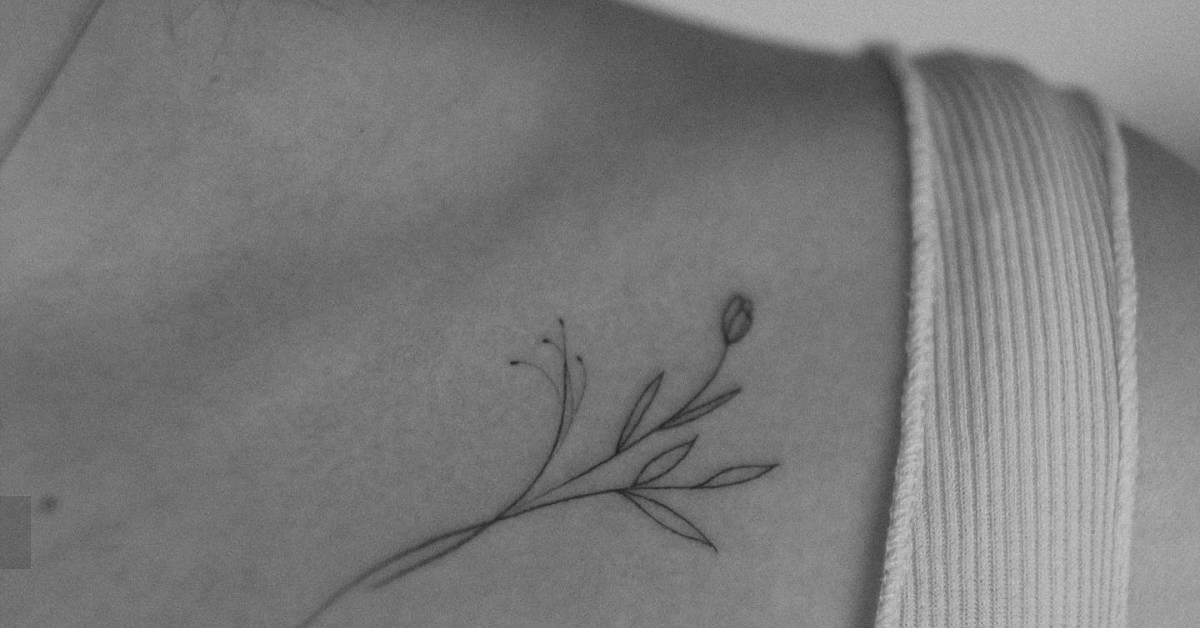 Fine line style tulip tattoo located on the collarbone.