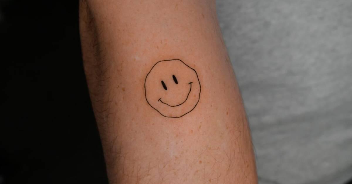 Minimalistic style smiley face tattoo located on the