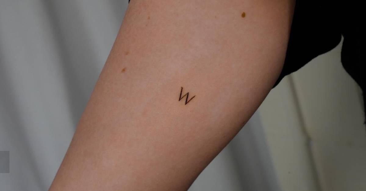 Minimalistic style letter "W" tattoo located on the