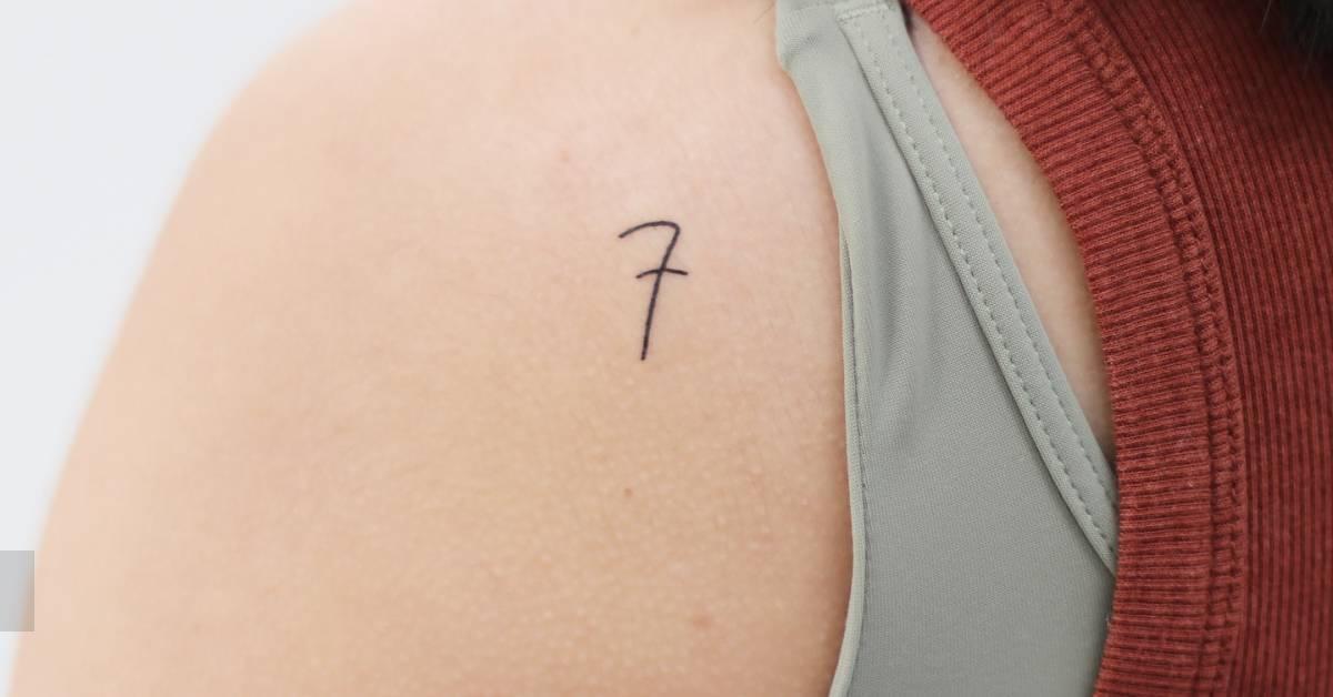 Minimalistic number "7" tattoo located on the shoulder
