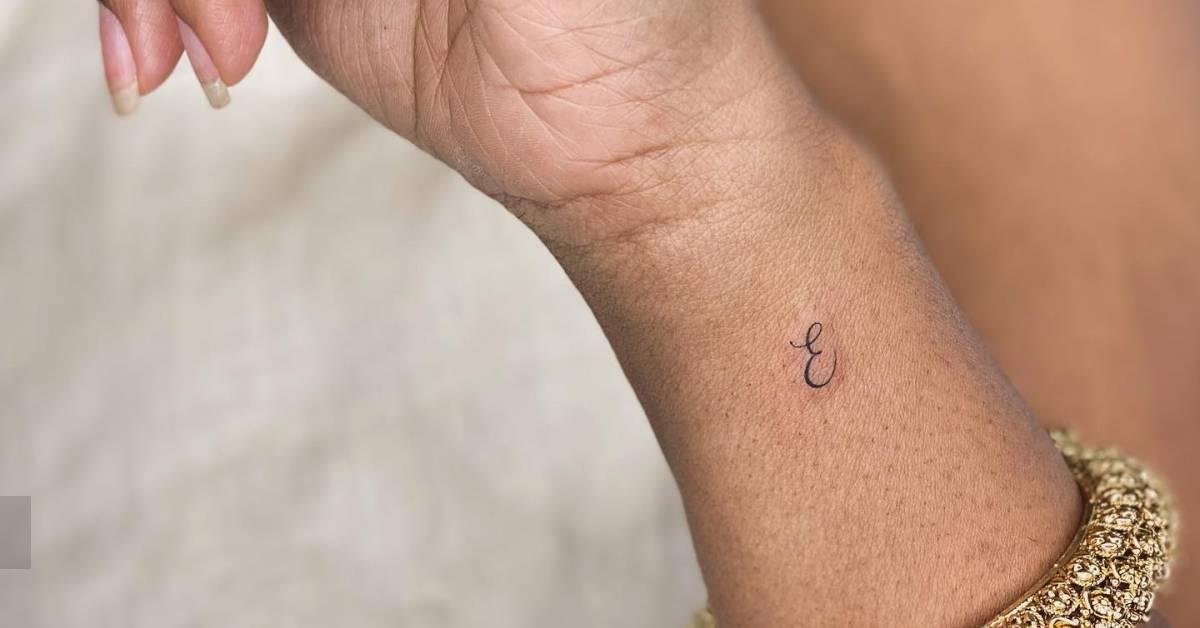 Minimalistic style letter "E" tattoo located on the