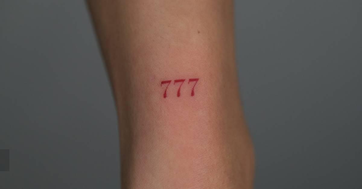 Number "777" tattoo in red ink located on the wrist.