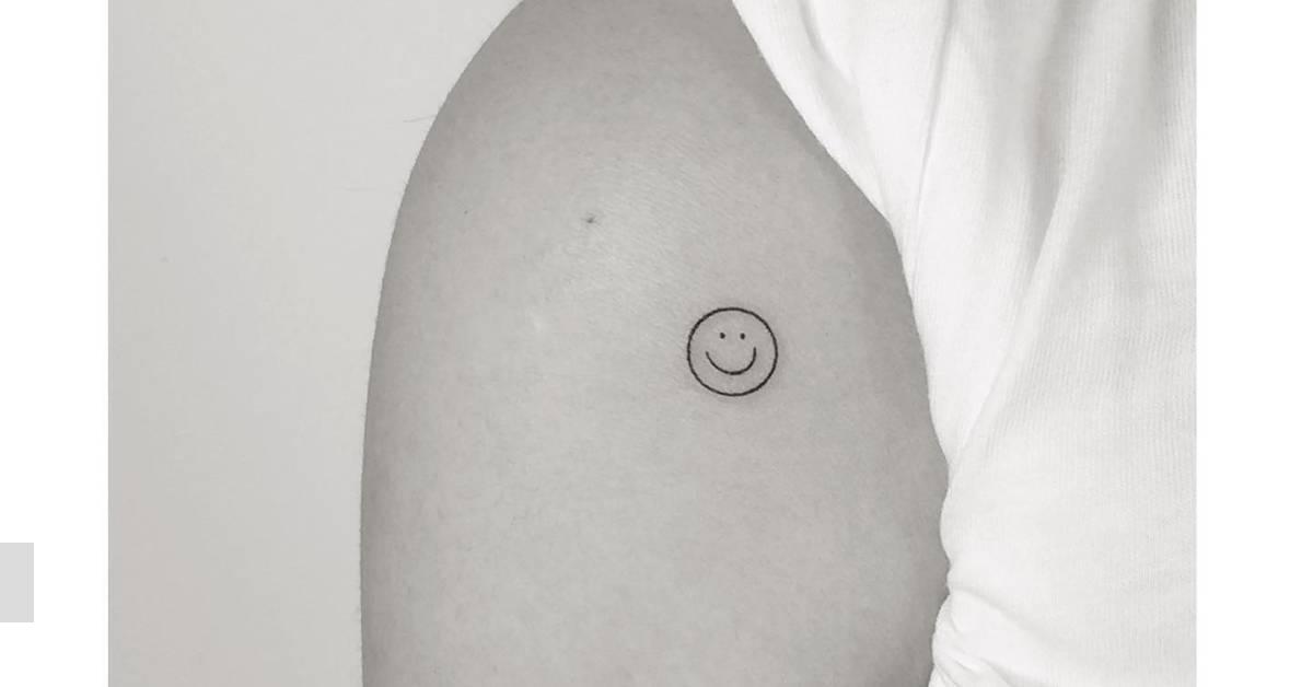 Minimalistic style smiley face tattoo located on the