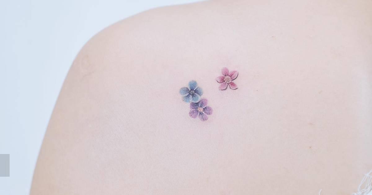 Watercolor style little flowers tattoo located on the