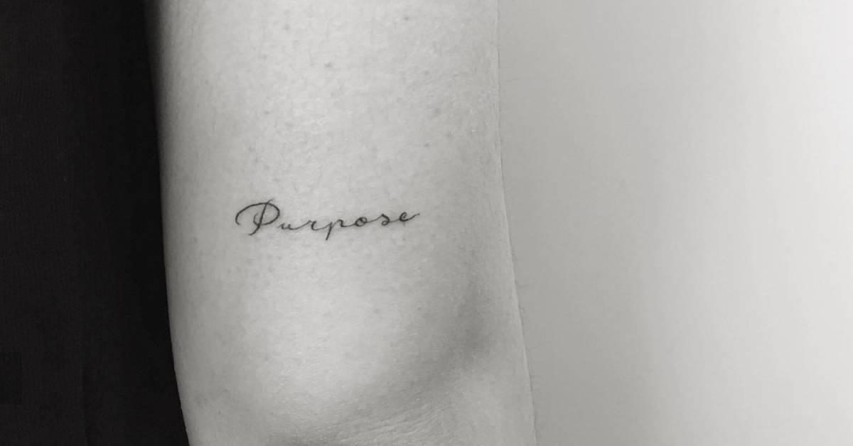 Word "purpose" lettering tattoo located on the tricep.