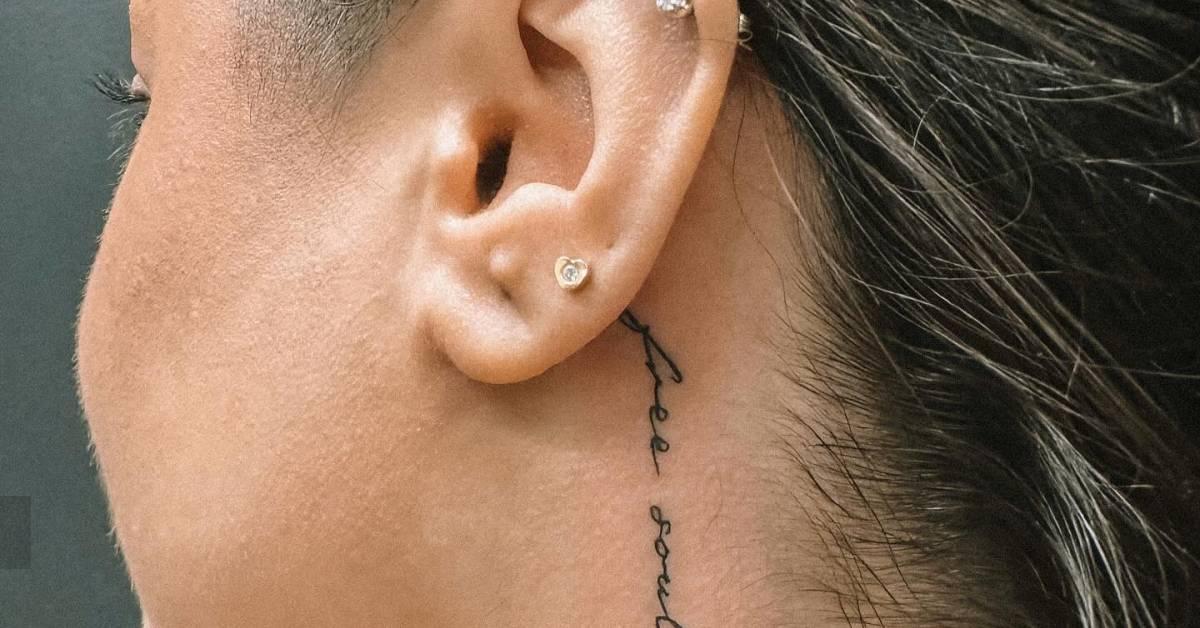 Handwritten word "free soul" tattoo located behind the