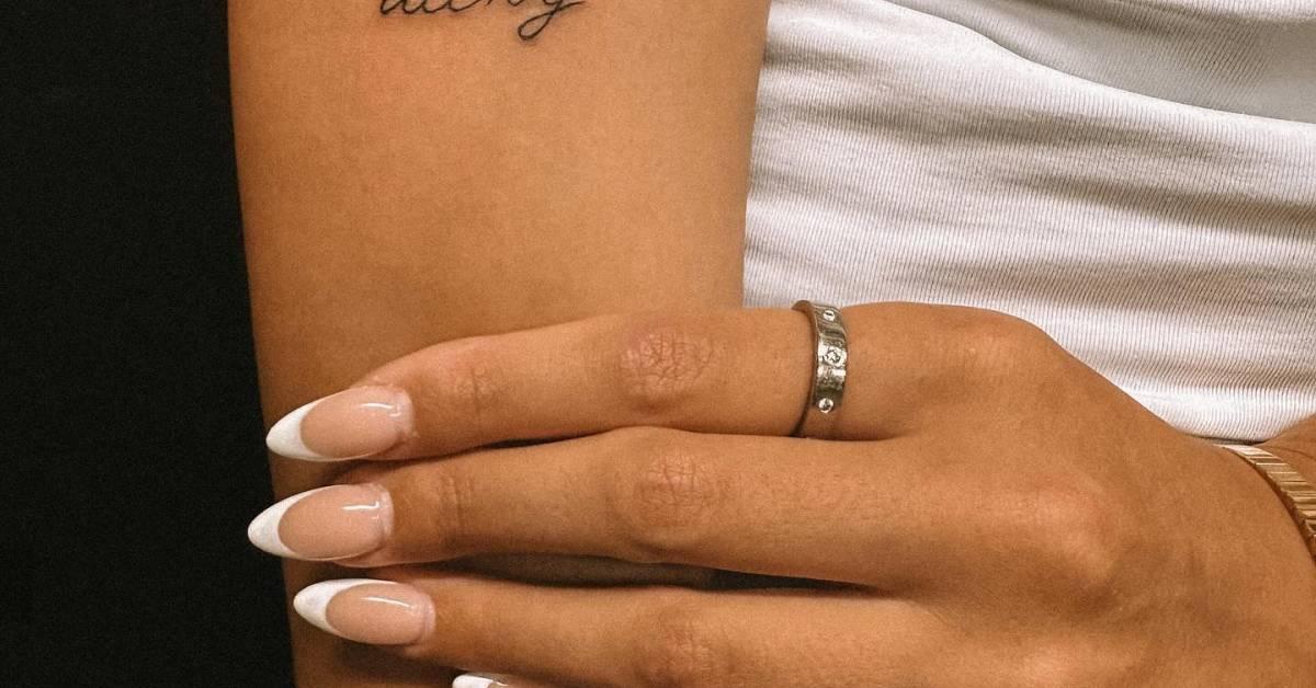 Handwritten word "lucky" tattooed on the inner forearm.