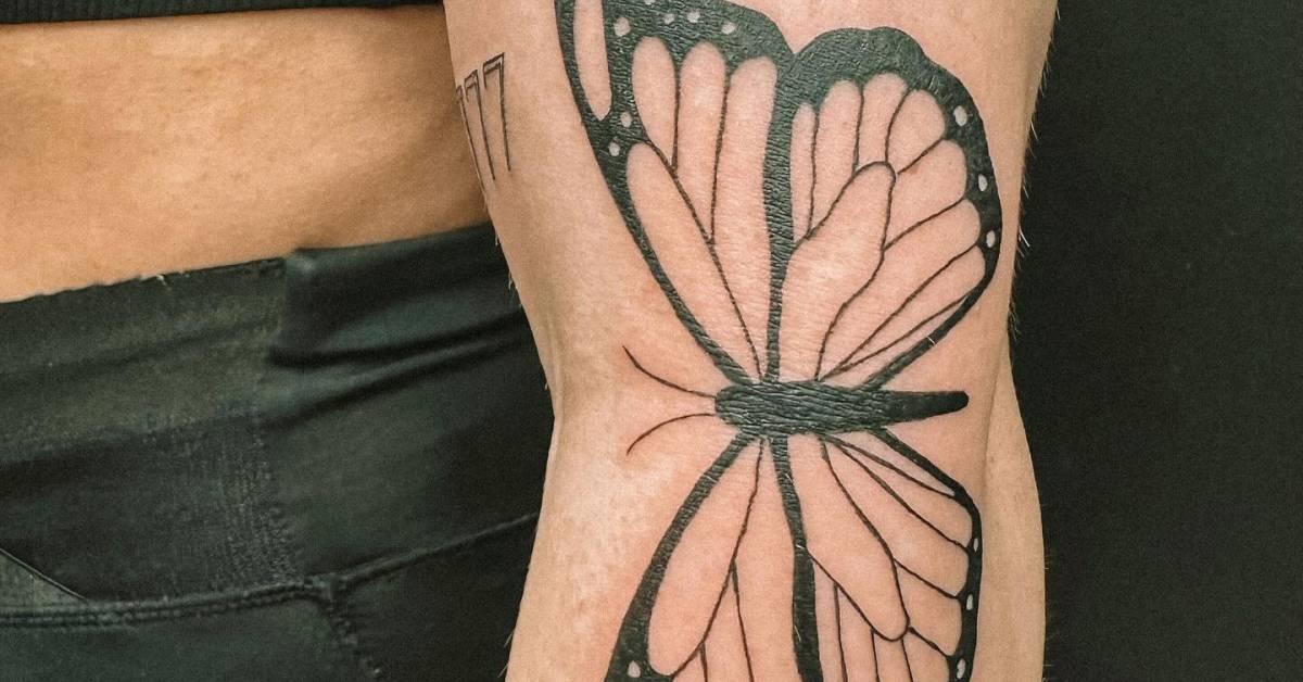 Blackwork style butterfly tattoo placed on the elbow.