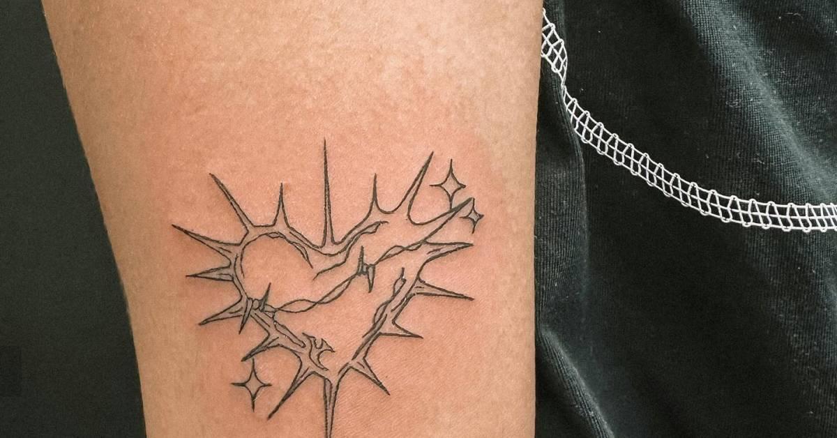 Fine line style spikey heart tattoo located on the