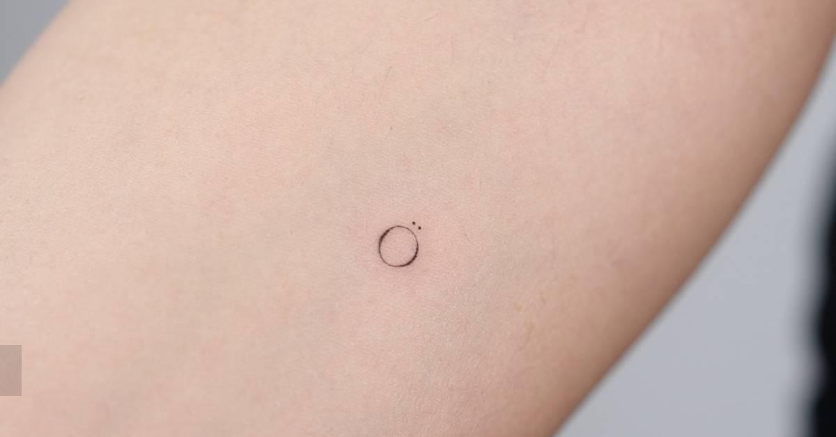 Tiny letter "O" tattoo located on the inner forearm.