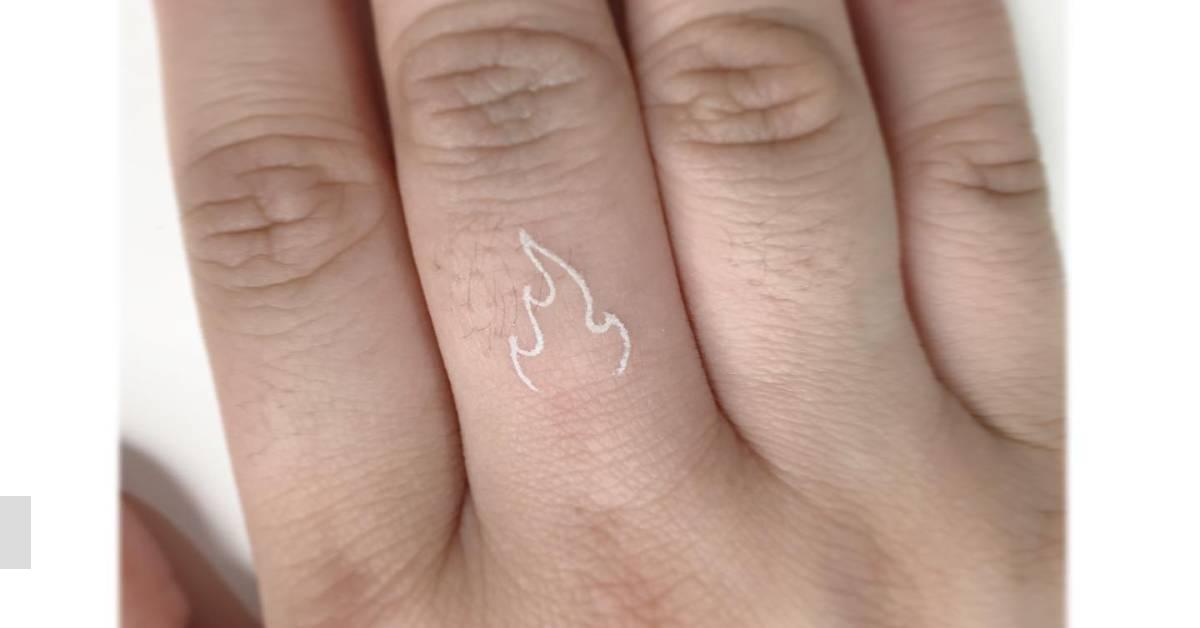 Tiny white fire tattoo located on the finger,
