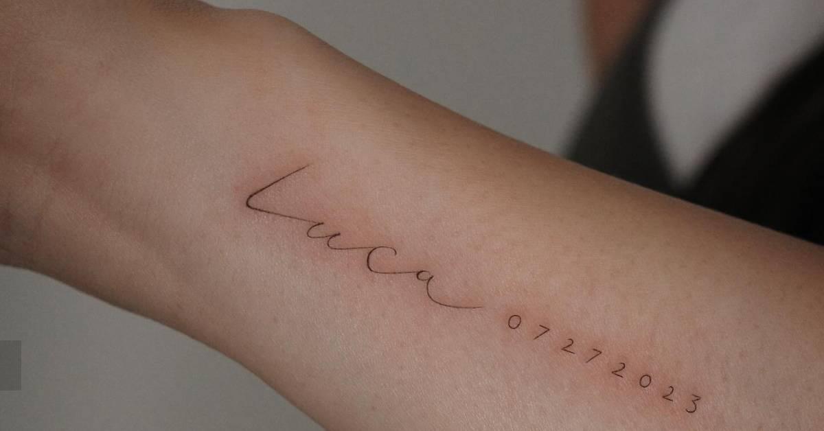 Name "Luca" and date lettering tattoo located on the