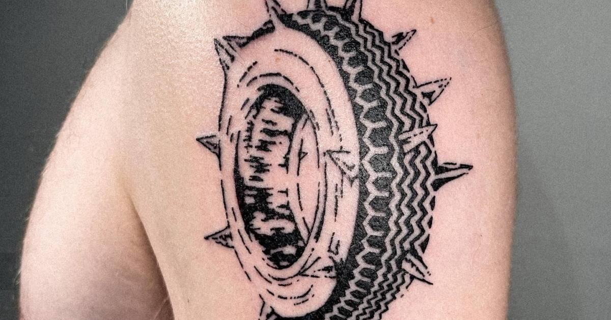 Spikey tire tattoo located on the upper arm, blackwork