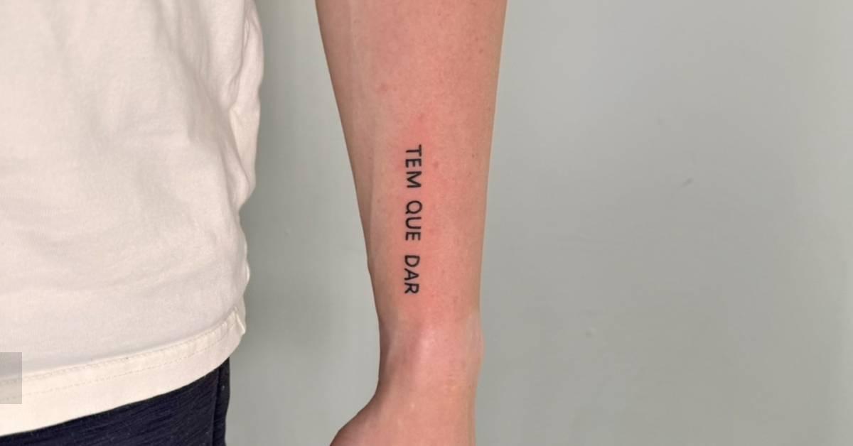 "Tem que dar" lettering tattoo placed on the wrist.
