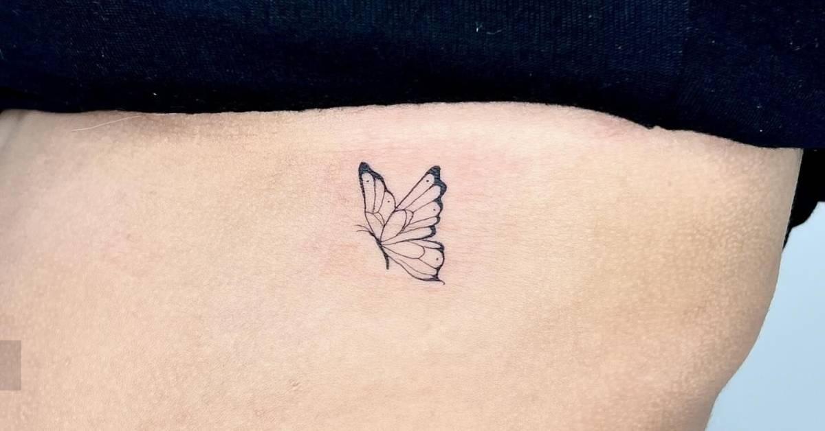 Fine line style butterfly tattoo placed on the rib.