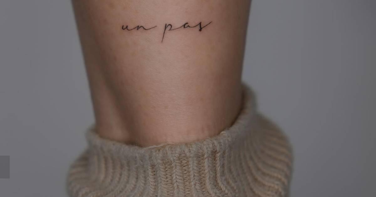 "Un pas" handwritten lettering tattoo placed on the