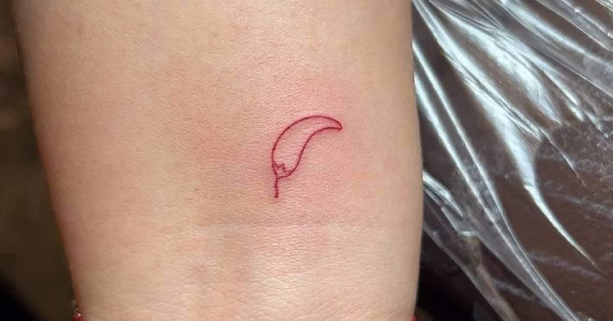 Minimalistic red chilli tattoo located on the chili.