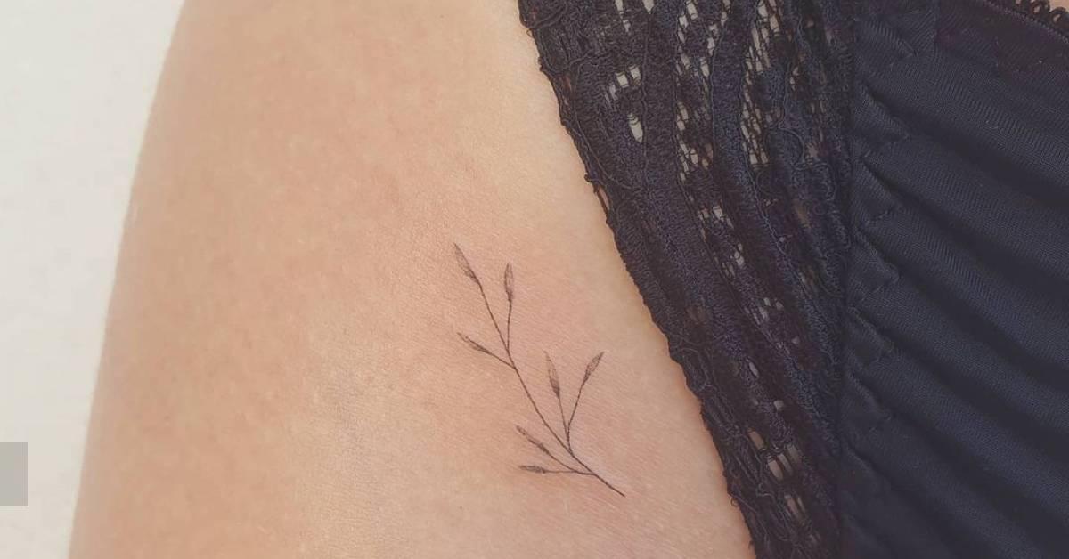 Fine line style sprig tattoo placed on the pelvis.