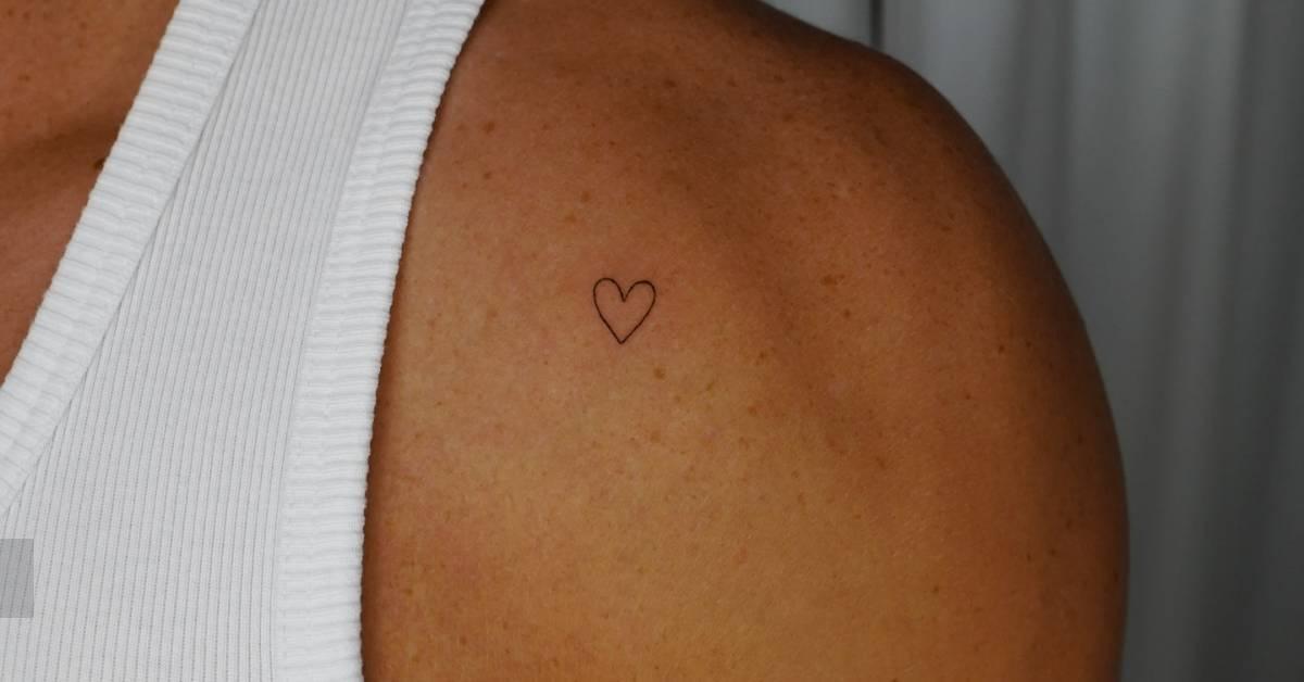 Tiny minimalistic heart tattoo located on the shoulder.