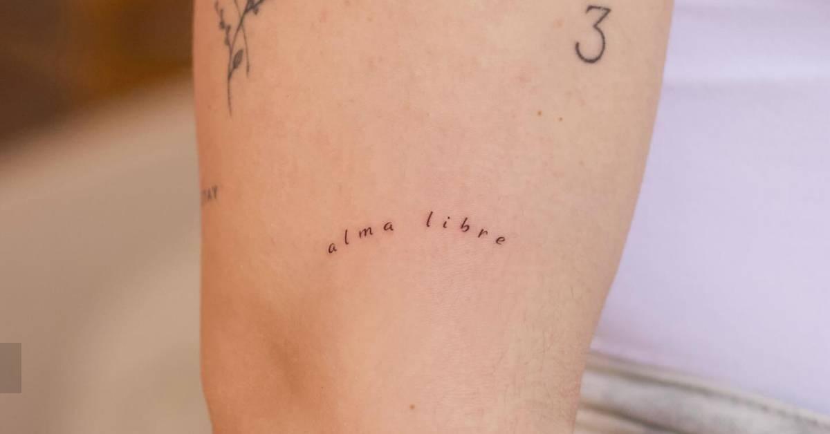 "Alma libre" lettering tattoo placed on the upper arm.