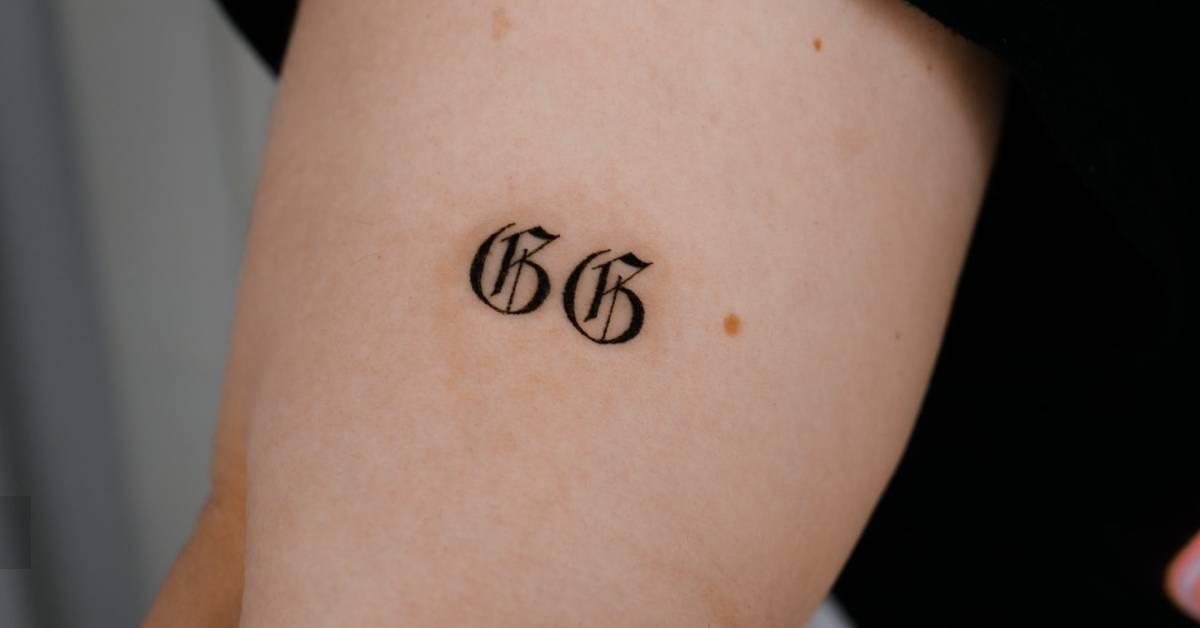 "GG" in gothic font tattooed on the upper arm.