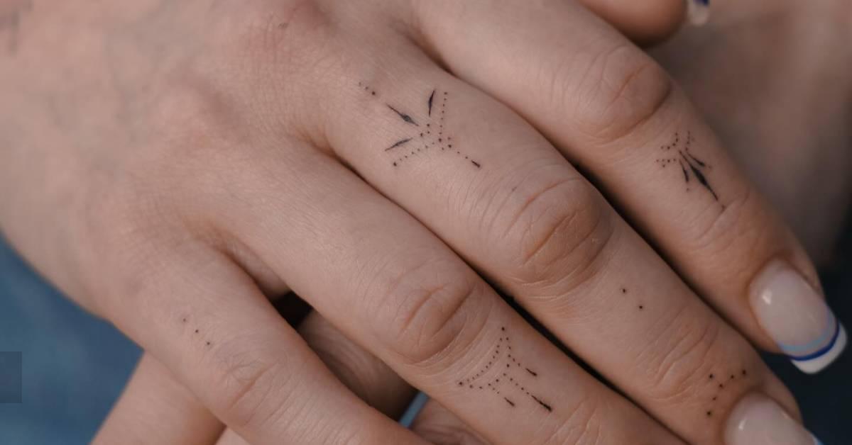 Hand poked ornamental finger composition tattoos.