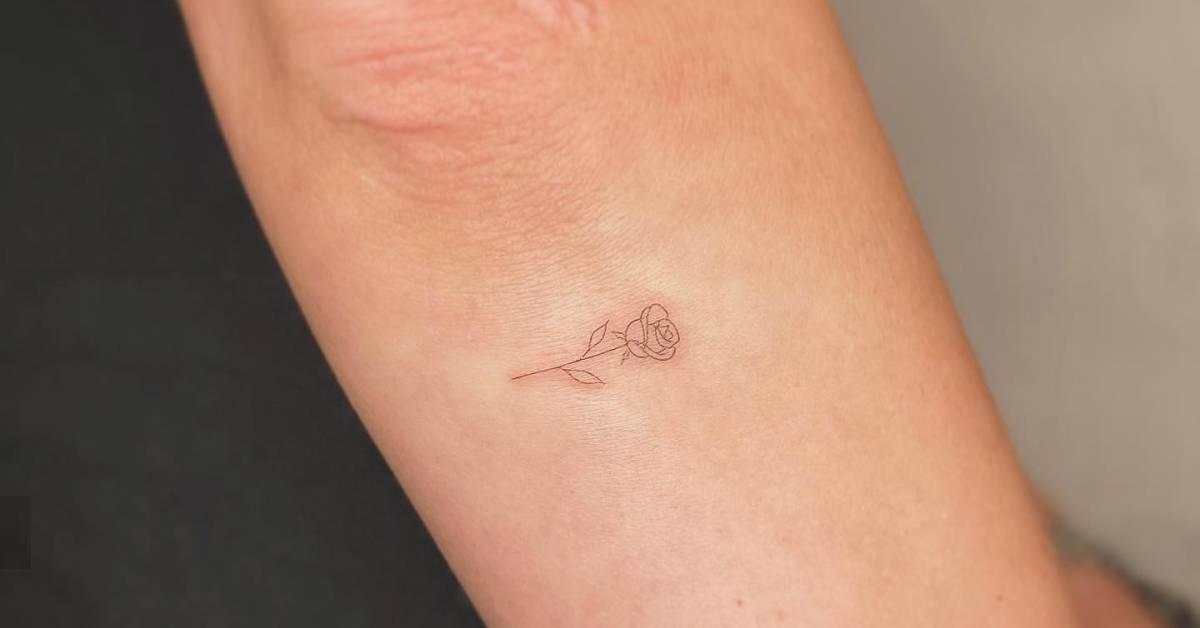 Tiny fine line style rose tattoo located on the