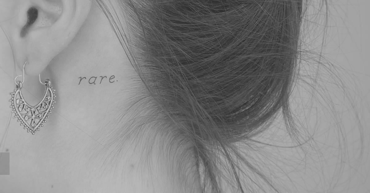 Lettering tattoo of the word "rare" located behind the