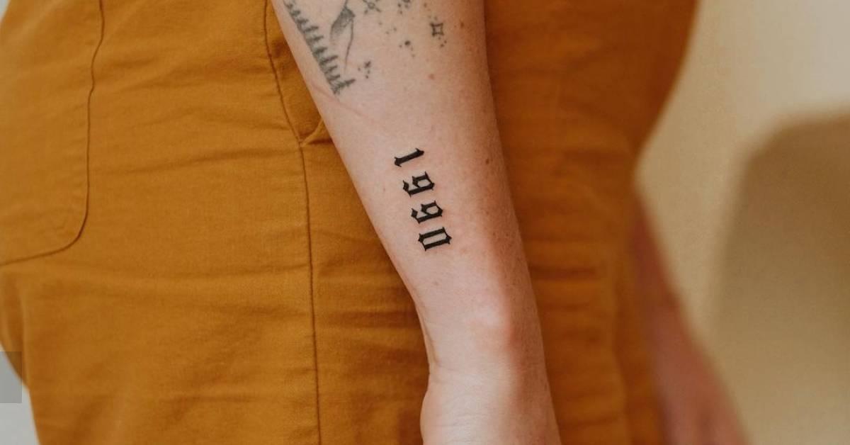 Gothic inspired "1990" typography tattoo located on the