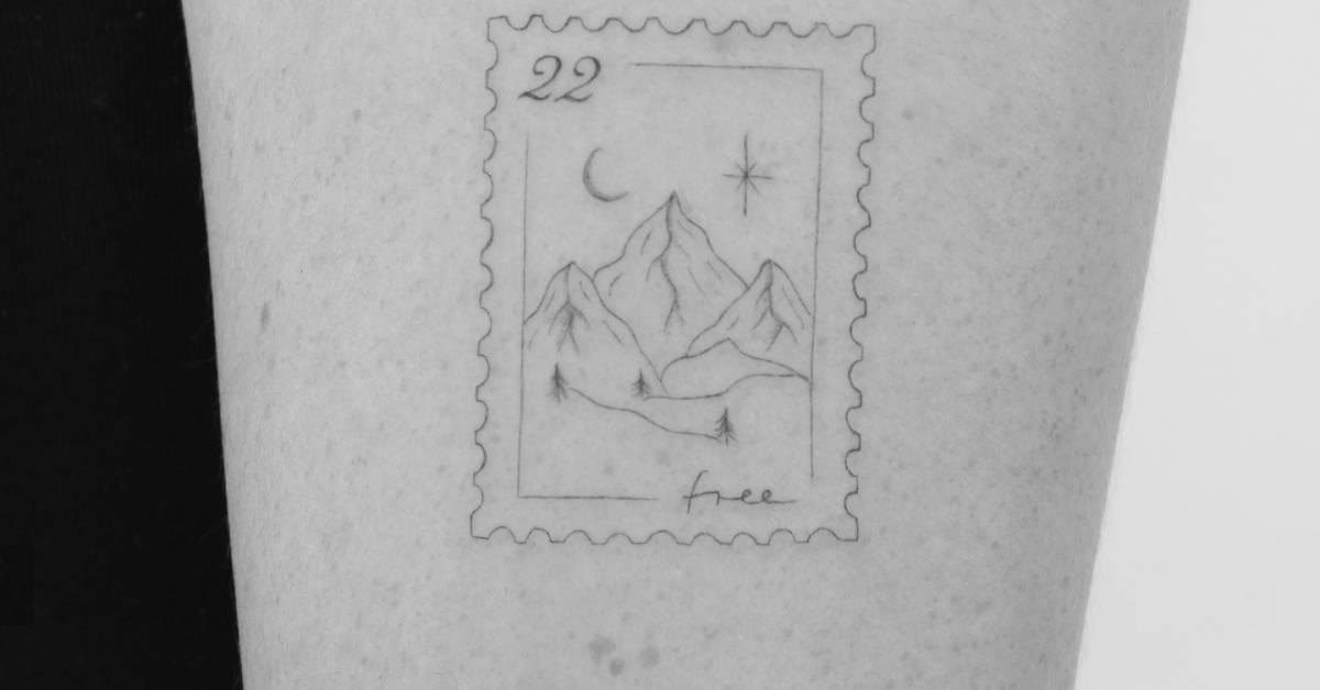 Fine line style mountain stamp tattoo located on the