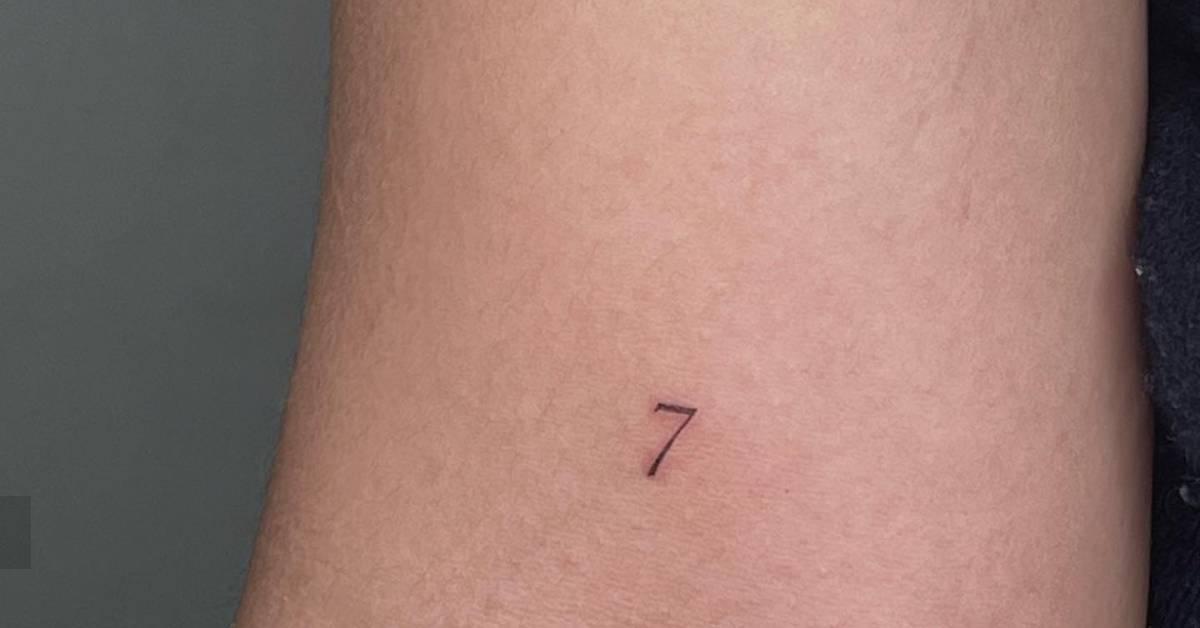 Tiny lettering tattoo of the number "7" located on the