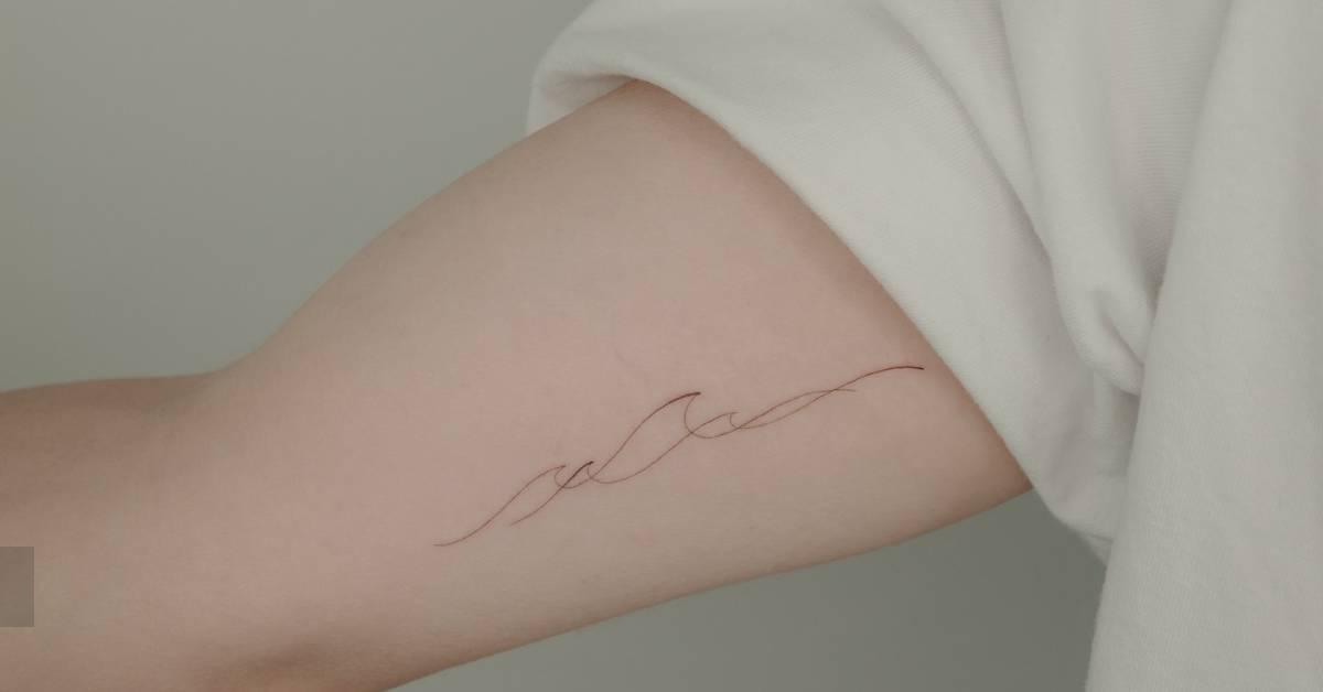 Fine line style waves tattoo placed on the inner arm.