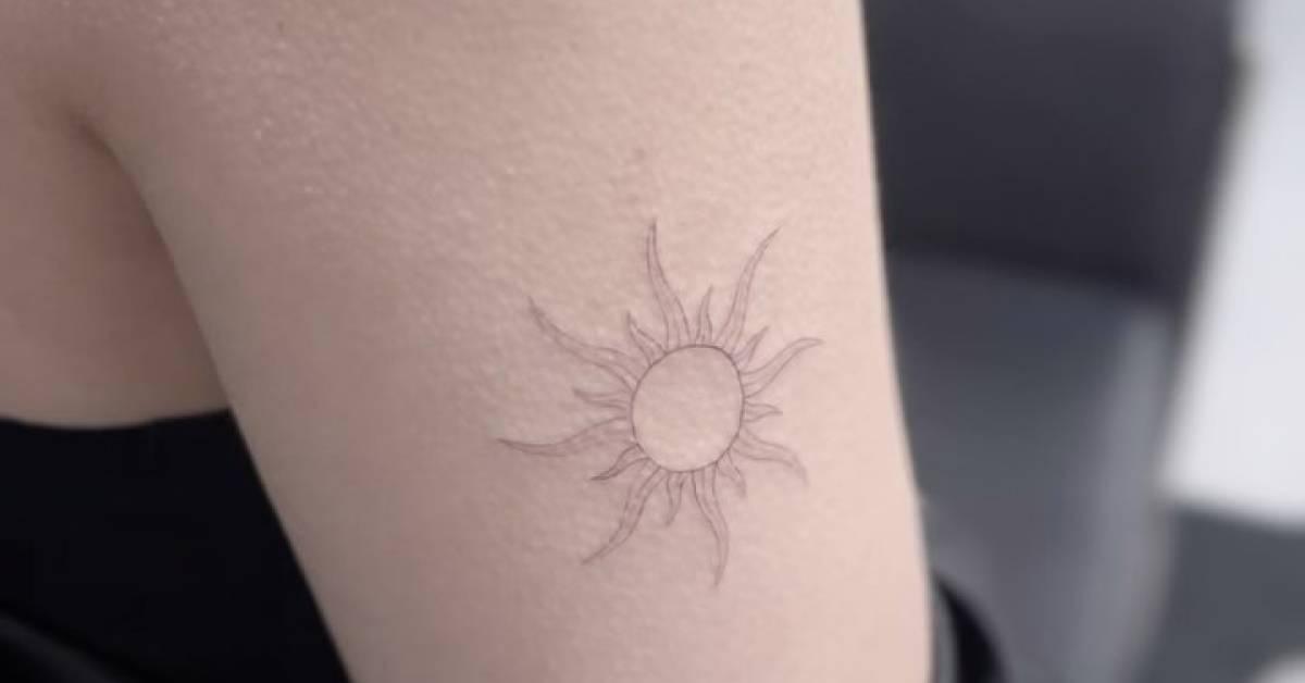 Sun tattoo in fine line style located on the upper arm.