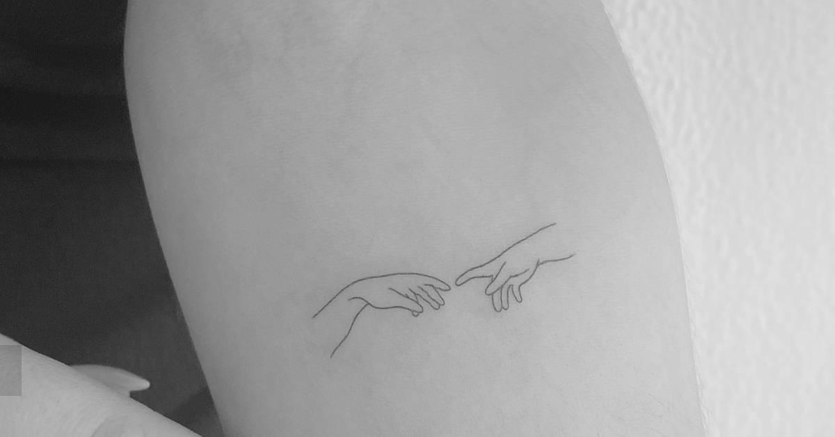 Fine line style 'The Creation of Adam' hands tattooed