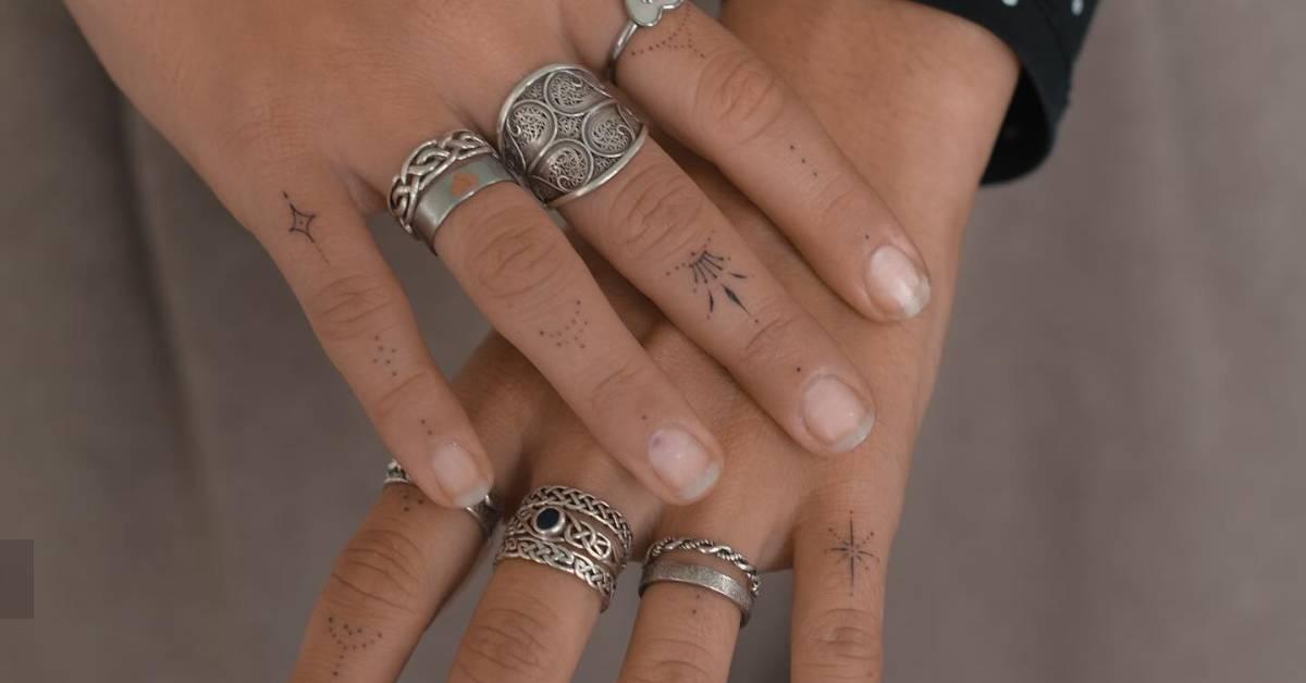 Hand poked ornamental finger composition tattoos.
