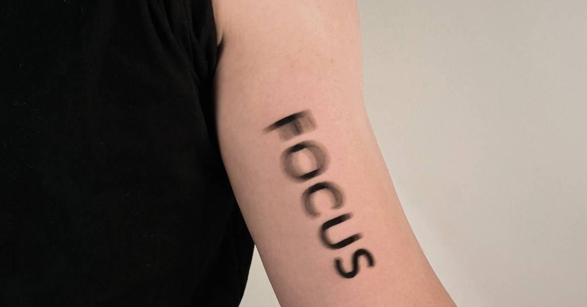 Blurry lettering tattoo of the word "focus" located on