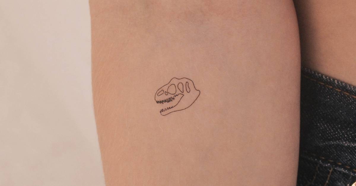 Fine line style t-rex skull temporary tattoo located on