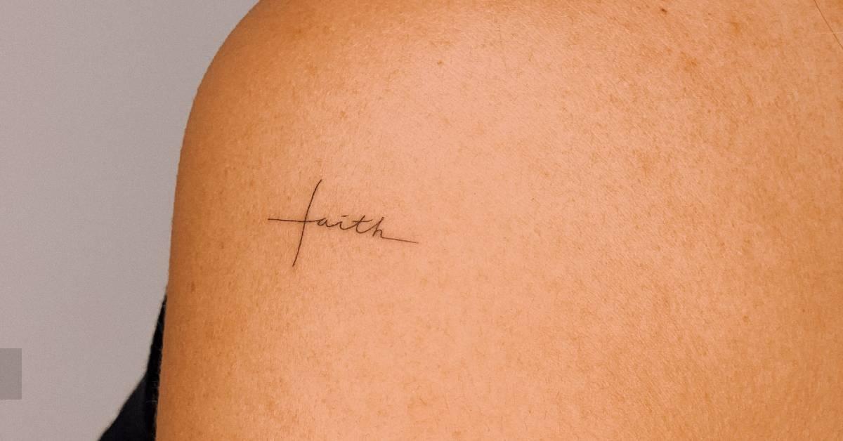 Handwritten "faith" cross tattoo located on the