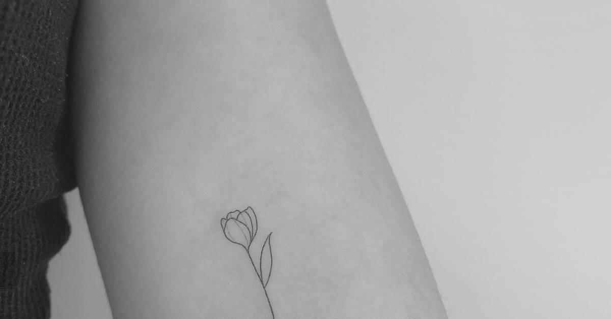 Fine line style tulip tattoo placed on the inner arm.