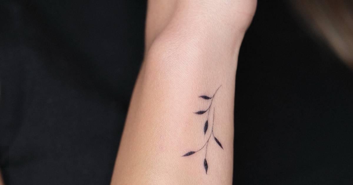 Minimalistic style sprig tattoo located on the wrist.