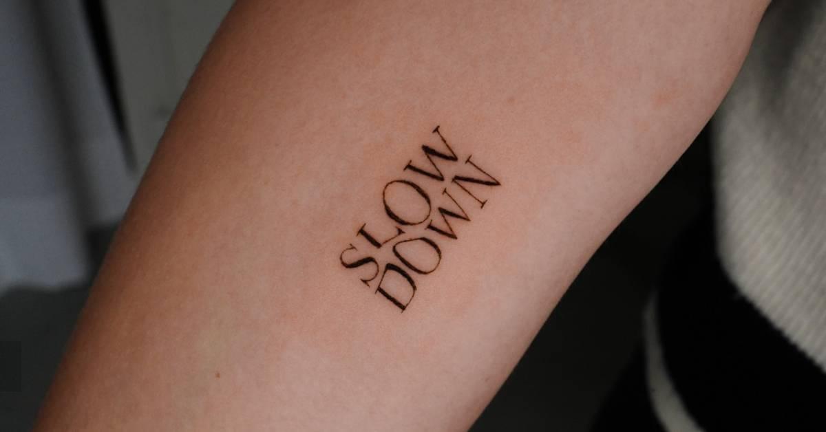 "Slow down" in serif font tattooed on the inner