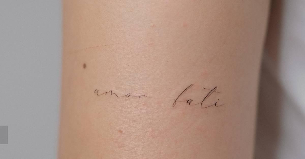 "Amor fati" lettering tattoo located on the tricep.