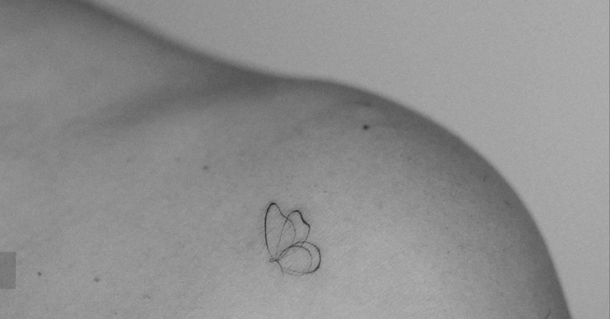 One line butterfly tattoo located on the shoulder.