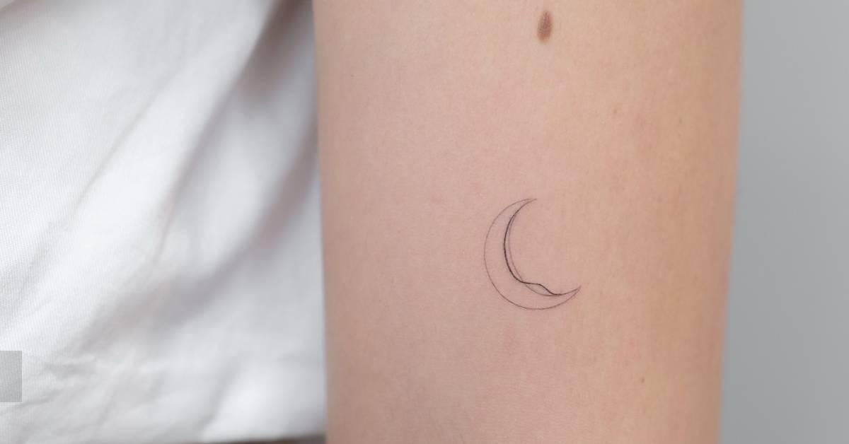 Fine line style crescent moon tattoo located on the