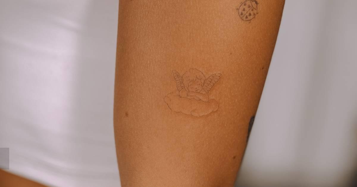 Fine line style cherub tattoo located on the upper arm.