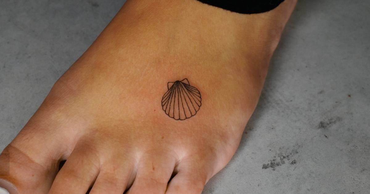 Fine line style scallop shell tattoo placed on the