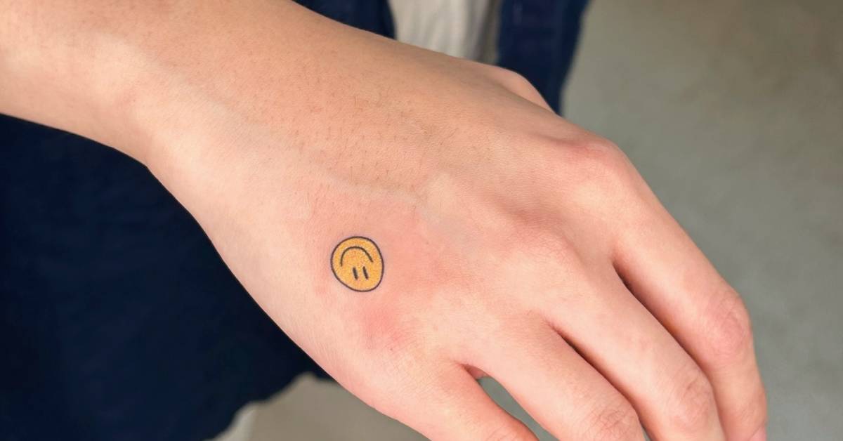 Smiley face tattoo located on the hand, minimalistic